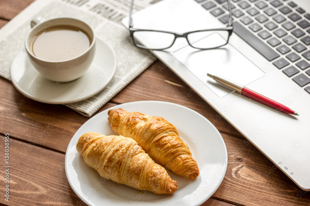 Foto de Stock Business lunch with croissant and laptop on wooden desk ...