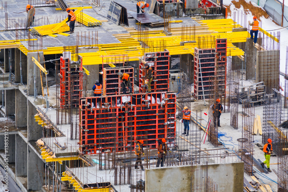 Construction site with a bright yellow formwork and builders in bright ...