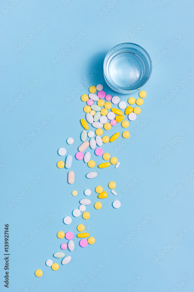 Colored pills with water on blue background. Stock Photo | Adobe Stock