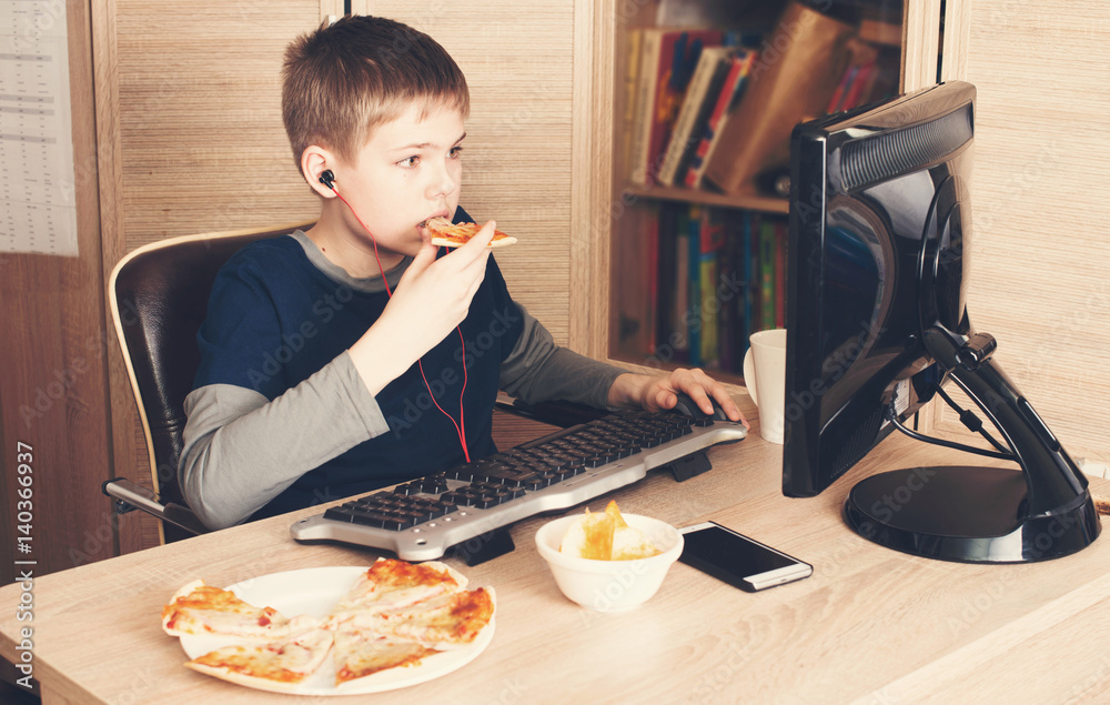 Kid eating pizza and surfing on internet or playing video games on PS ...