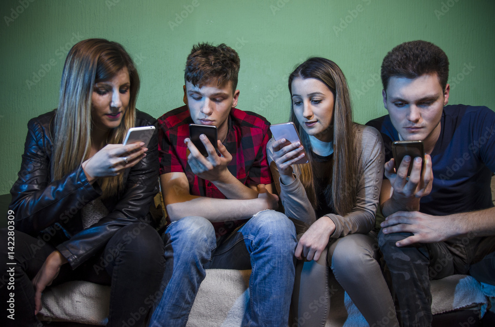 Group of teenagers and young adults staring at smartphones and not ...