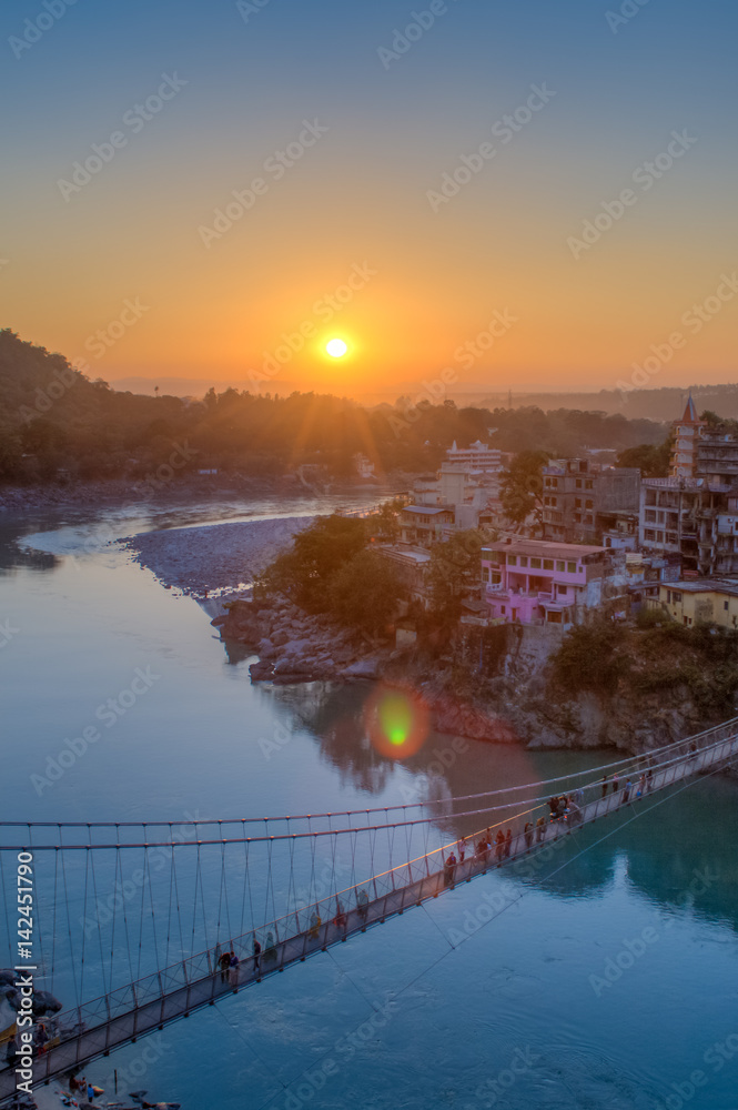 View of River Ganga and Ram Jhula bridge at sunset with a blue sky and ...