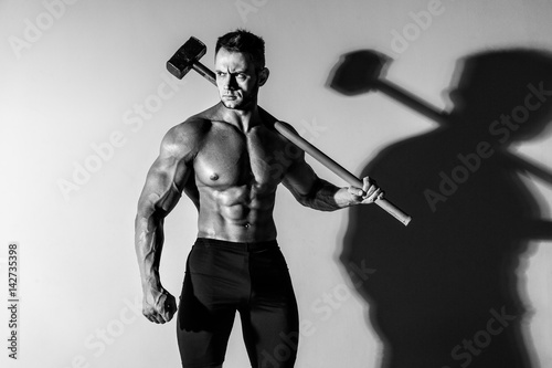 athlete and hammer. guy with a nice muscle fitness, bodybuilder hold ...