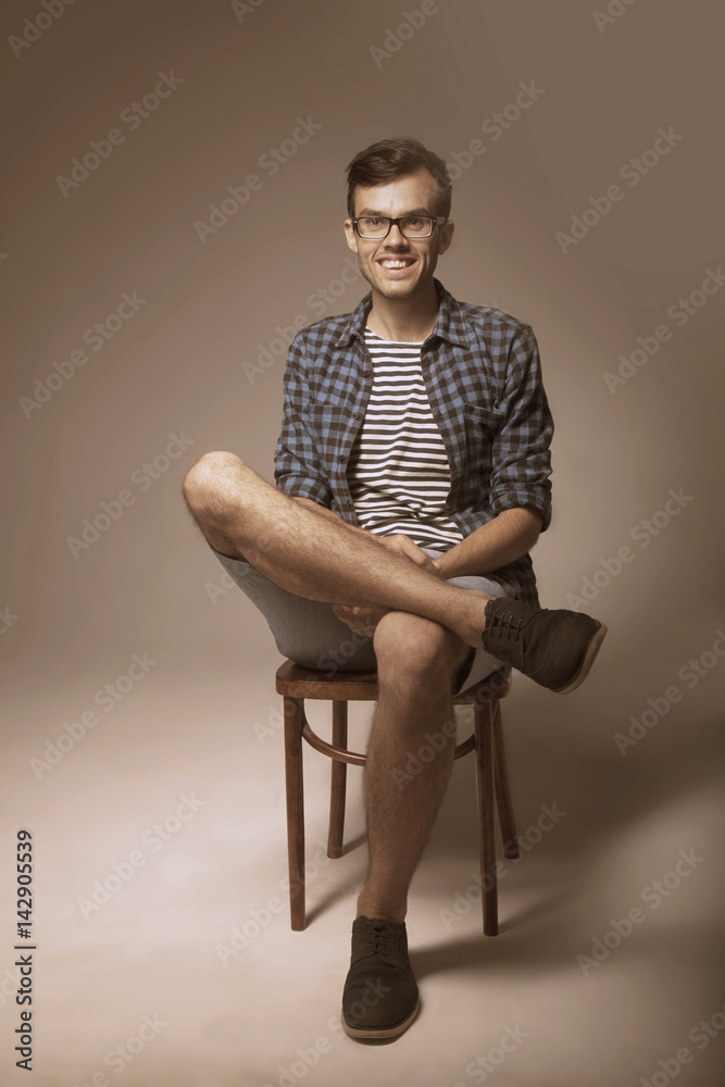 Successful young man sitting on vintage chair with his crossed legs as ...