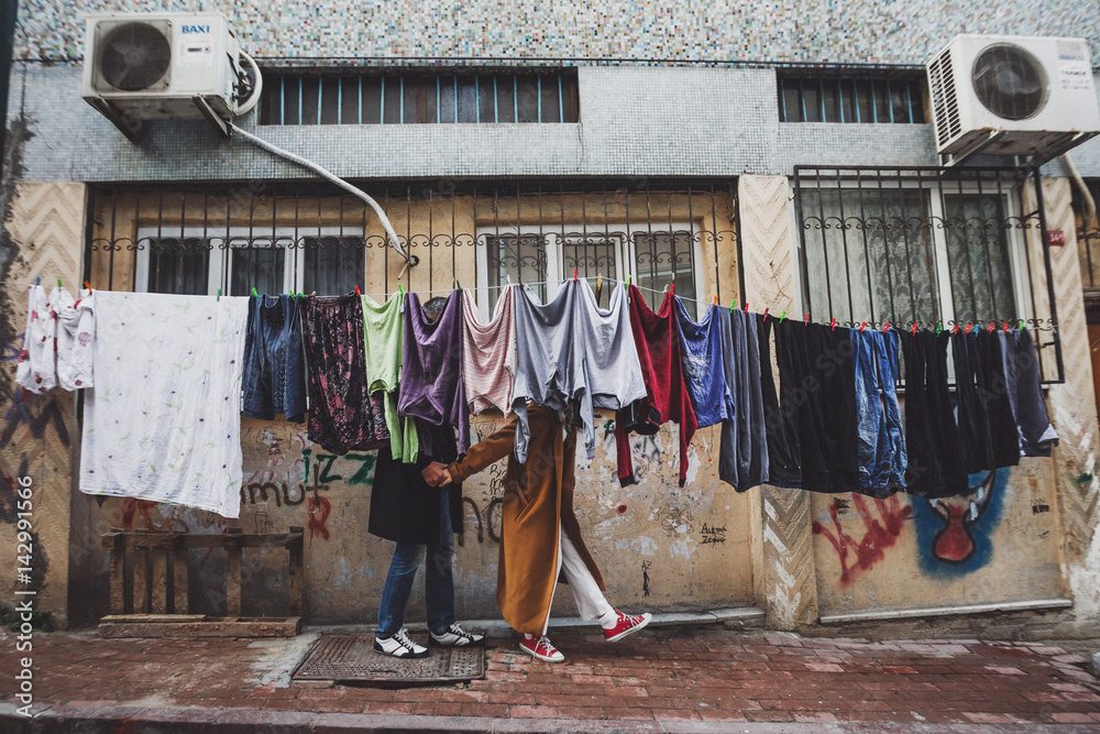 Young couple having fun in drying laundry hanging at old streets of ...