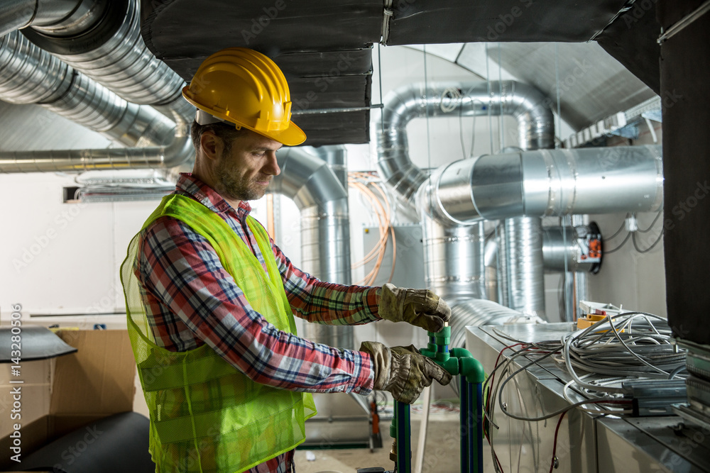 Worker making final touches to HVAC system. HVAC system stands for ...