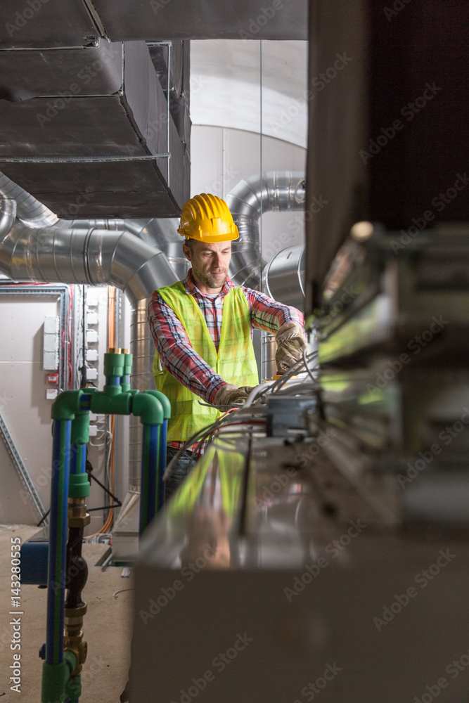 Worker making final touches to HVAC system. HVAC system stands for ...