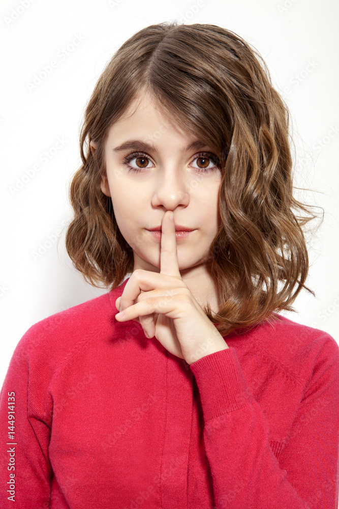 Young girl making a keep quiet gesture isolated on white background ...