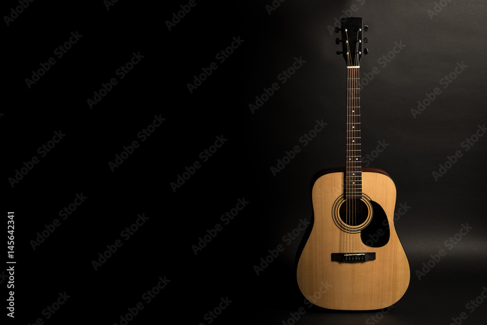 Acoustic guitar on a black background on the right side of the frame ...