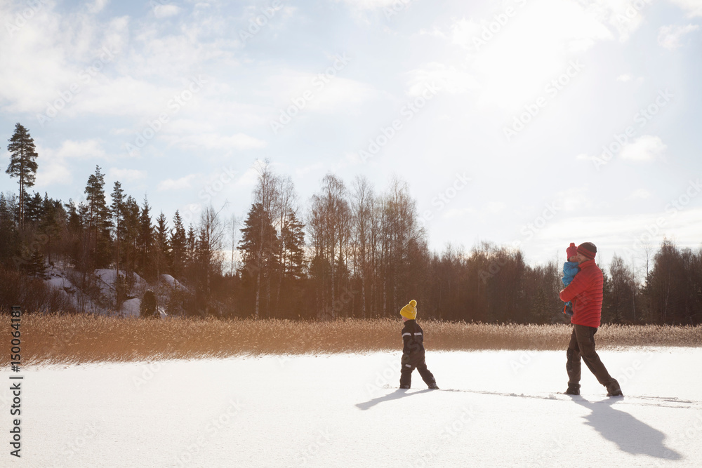 Father and two sons, walking through snow covered landscape Stock Photo ...