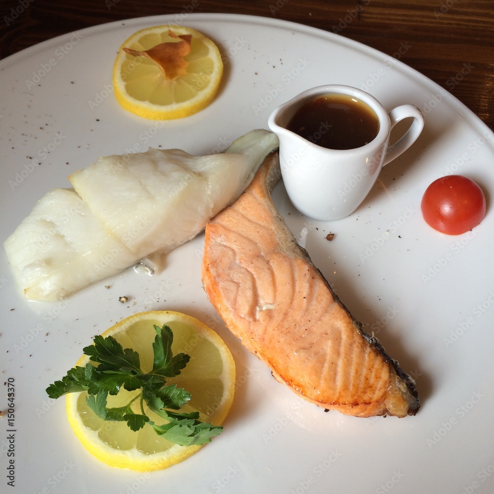 Pan fried salmon and cod fish with dressing salad sauce garnish with ...