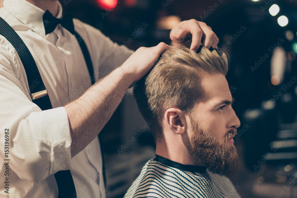 Attractive classy dressed barber shop hairdresser is turning client`s ...