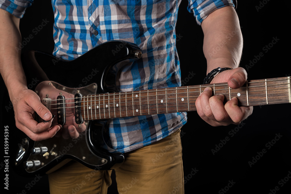 Music and art. Electric guitar in the hands of a guitarist, on a black ...