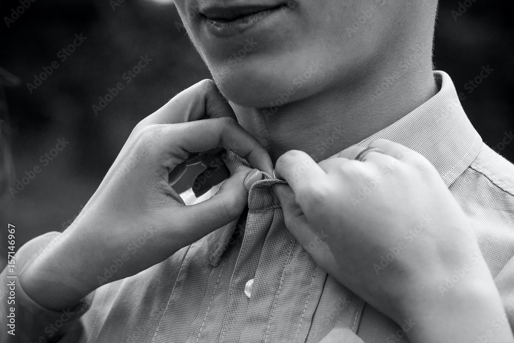 The hands of the bride fasten the button to the groom close-up ...