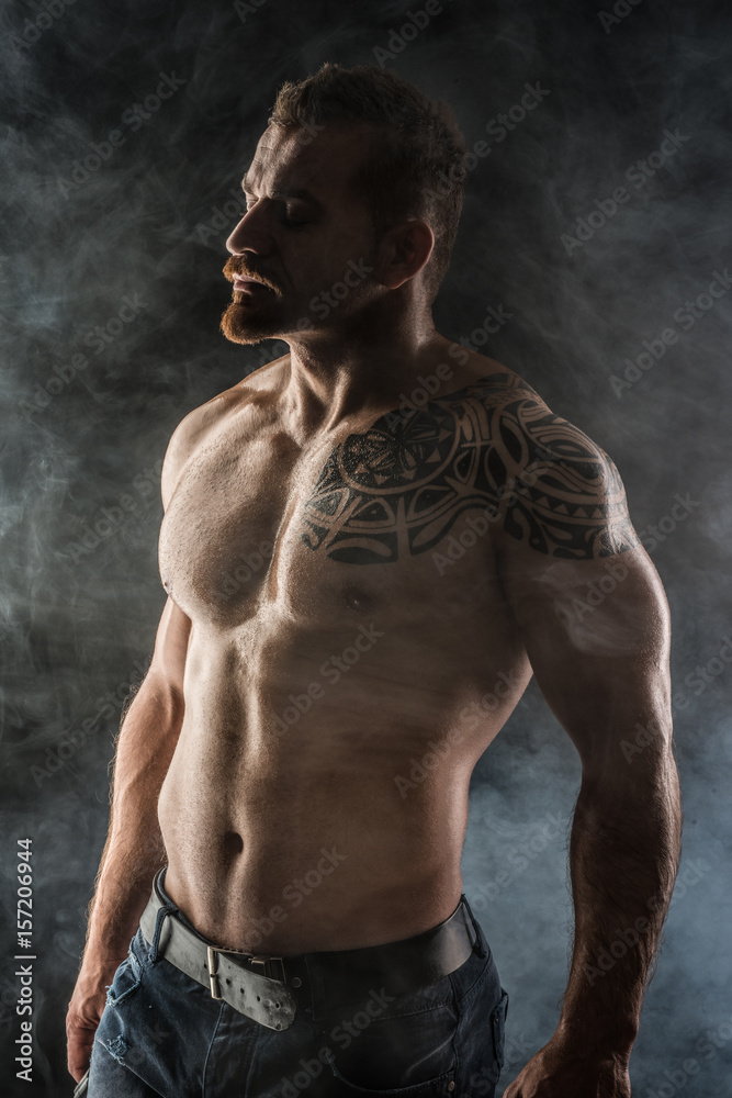 Athletic big guy posing in smoke fog black background. Wearing jeans ...