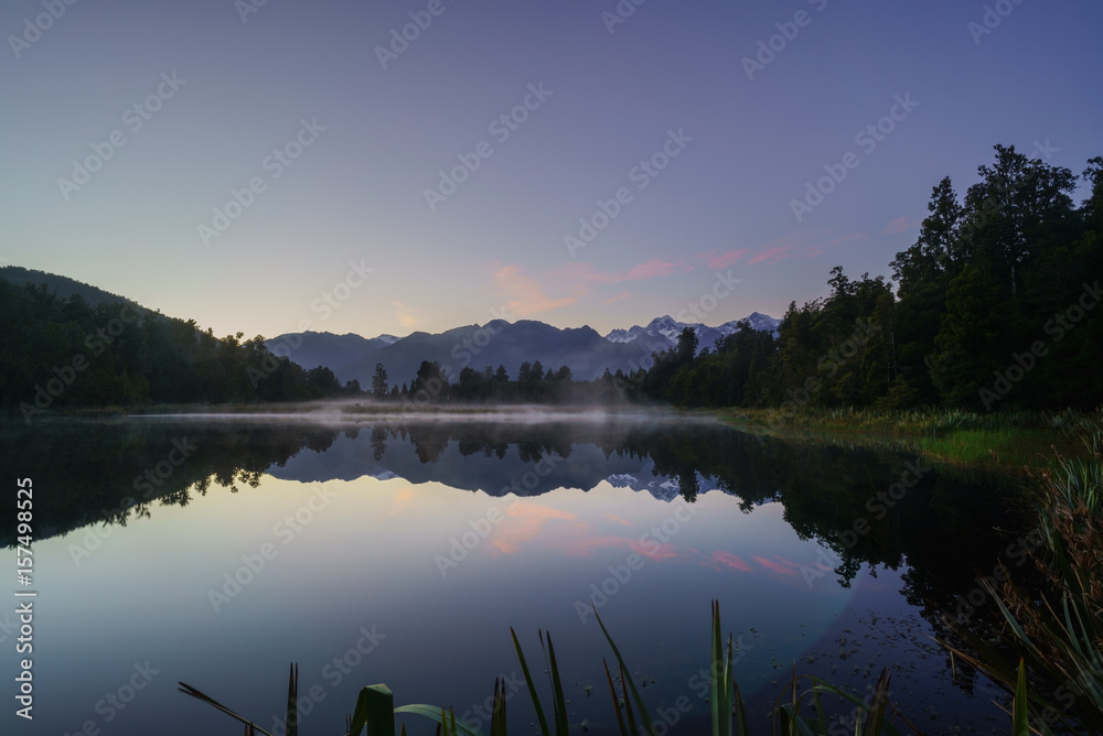 Beautiful reflection of Lake Matheson in twilight at sunrise with mist ...