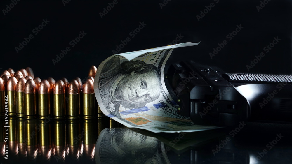 Bullets and US dollar bill on the black mirror floor. Bullets are a ...