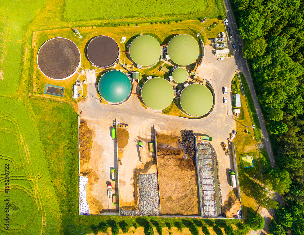 Aerial view over biogas plant and farm in green fields. Renewable energy from biomass. Modern ...