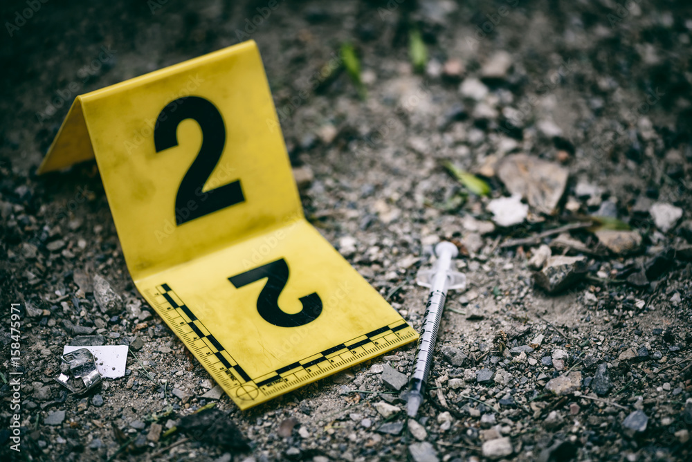 Crime scene marker next to tossed syringe on the ground 스톡 사진 | Adobe Stock