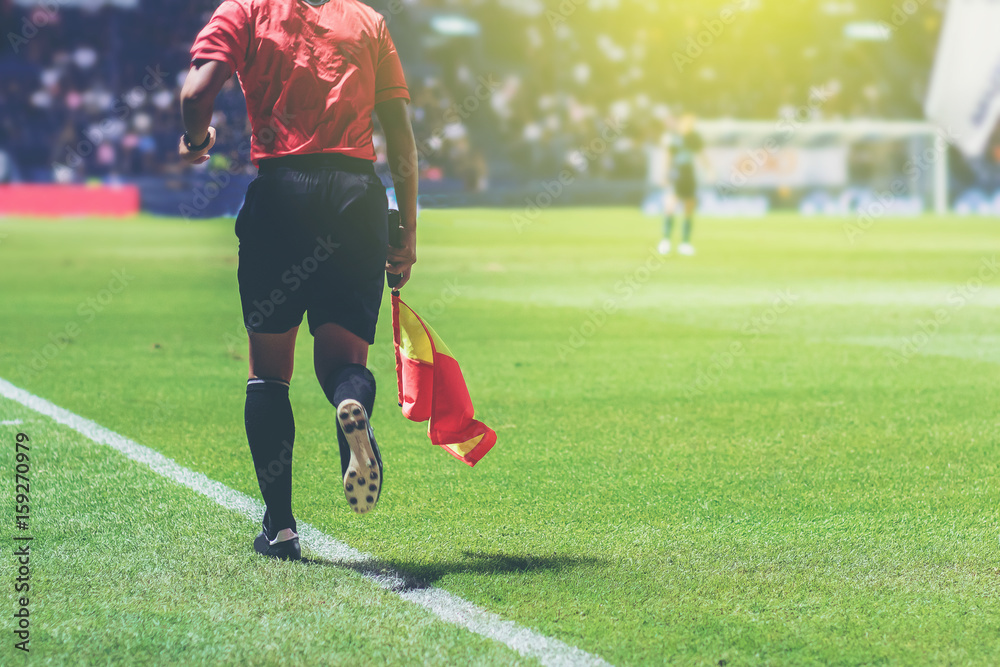 Lineman assistant referee with flag running at beside of a soccer field ...