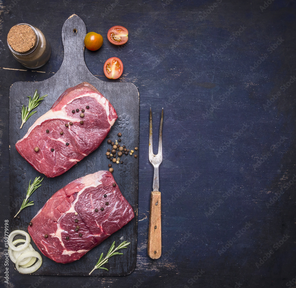 two raw ribeye steak on vintage cutting board with rosemary, herbs ...