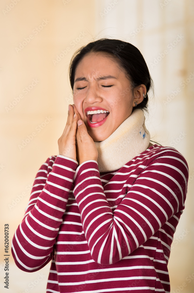 Young hispanic woman posing for camera wearing neck brace, showing ...