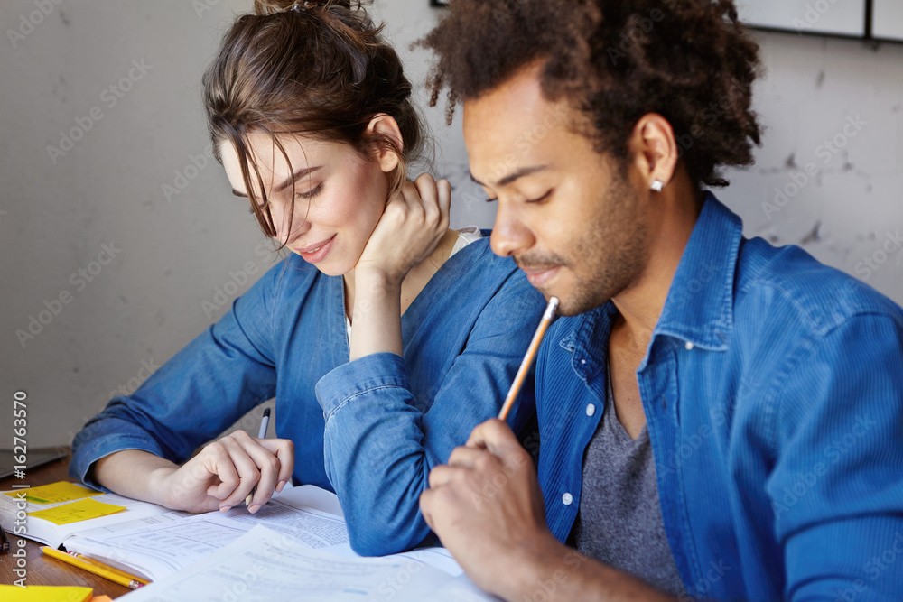 Side view of two students studying together, discussing homework ...