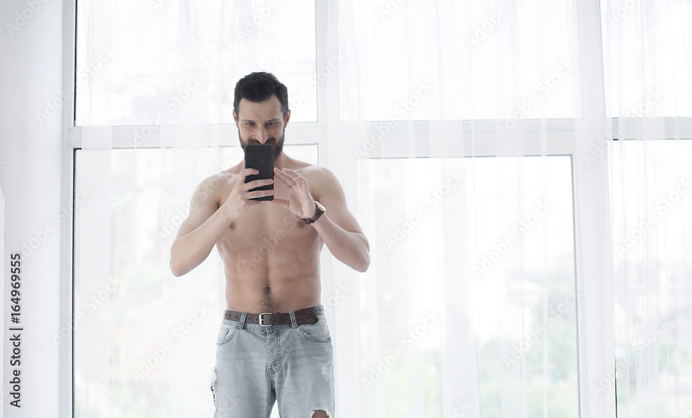 Handsome shirtless muscular bodybuilder man in jeans taking selfie with ...