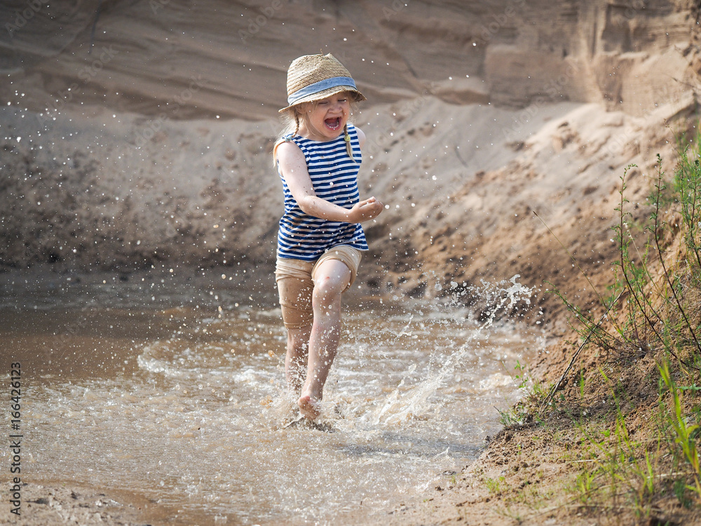 Incredibly happy child running fast on the water. Sand pit, muddy water ...
