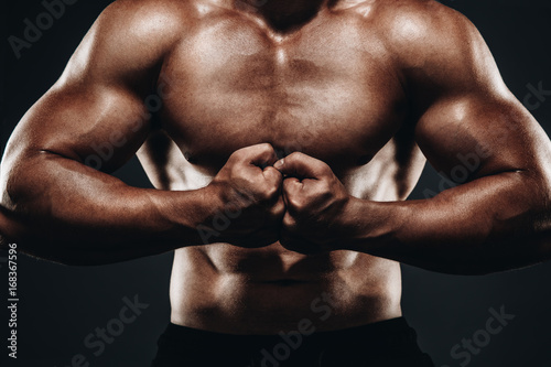 Strong athletic bodybuilder with muscular arm ands fist , perfect abs ...