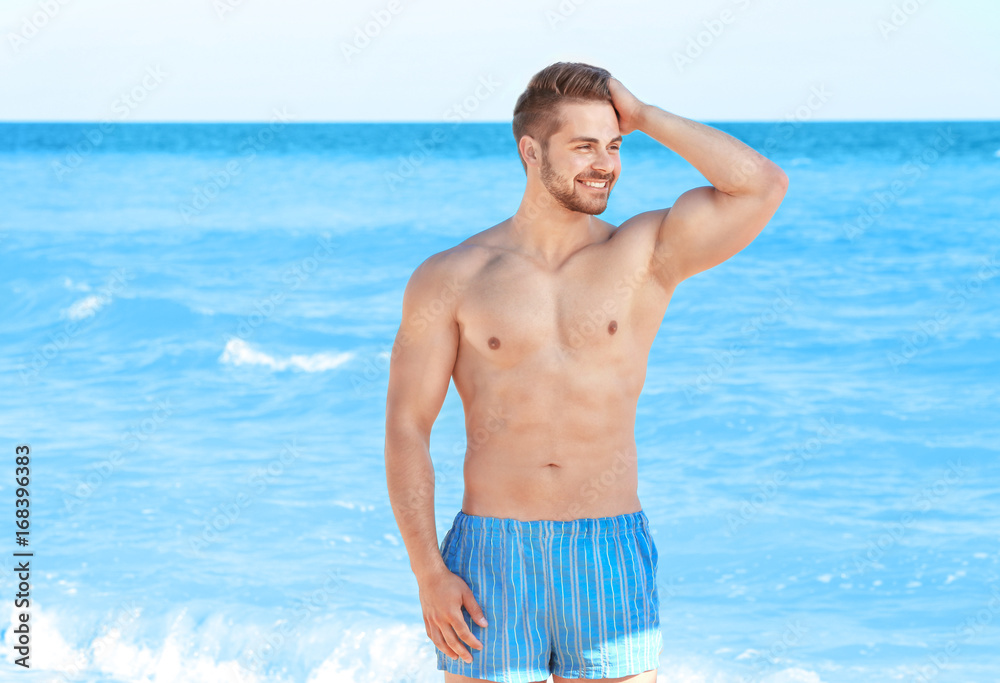 Handsome young muscular man in swimwear on sea background Stock Photo ...