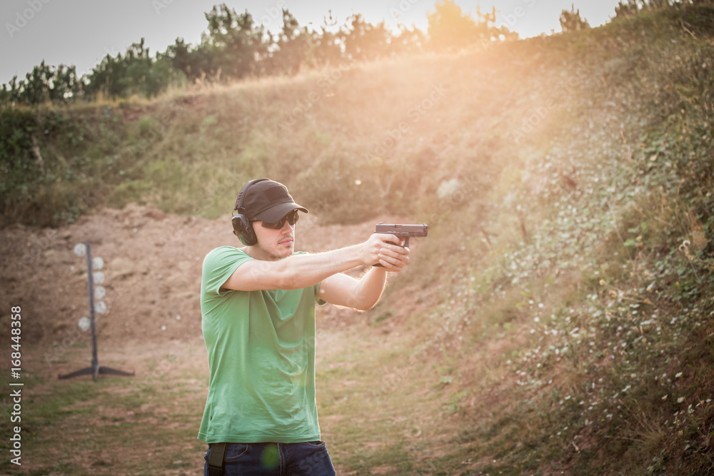 Handsome and muscular caucasian handsome guy firing from fire gun ...