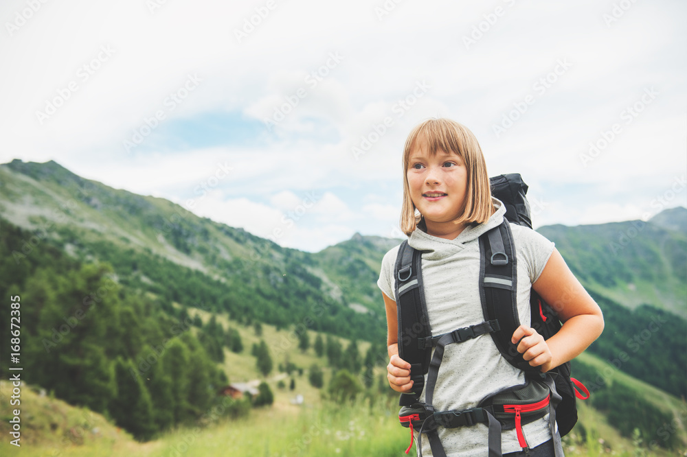 Happy little girl hiking in swiss Alps, wearing black backpack, travel ...