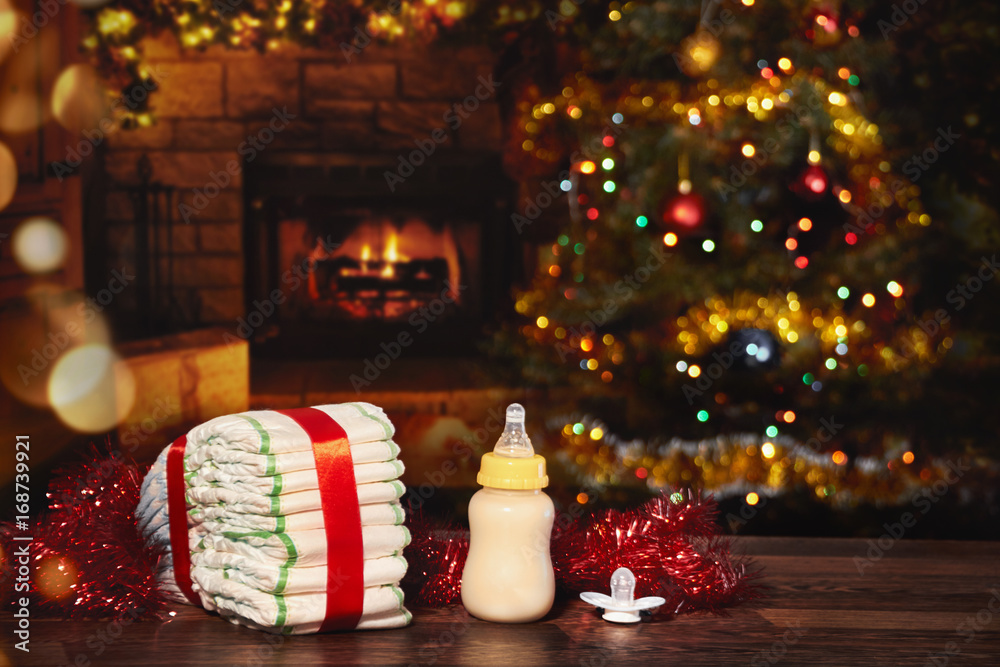 Baby bottle with milk, diapers and nipple on table. Christmas holiday ...