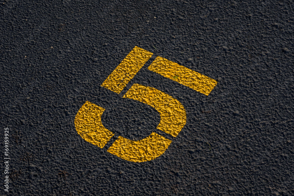 stenciled number 5 five in yellow paint on blacktop in parking lot ...