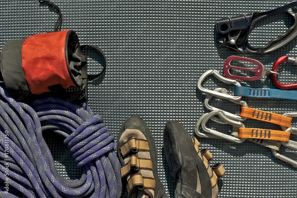 Top view of rock climbing equipment on grey mat. Chalk bag, rope ...