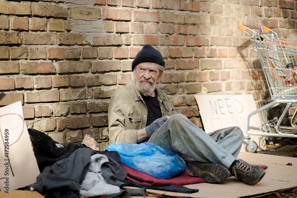 Tramp sitting in the street, his thigns scattered around him. Old ...