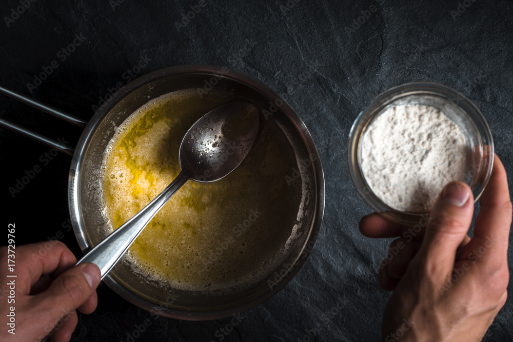 Stock-Foto „Flour is poured into a saucepan with melted butter close-up ...