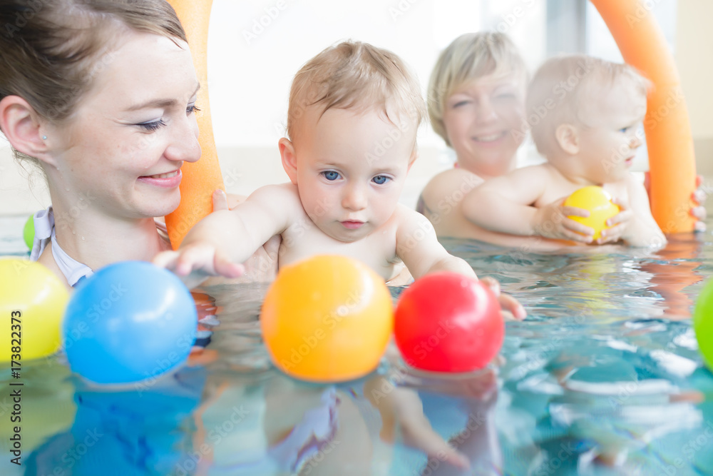 Mothers and their kids having fun at baby swimming lesson between lots ...