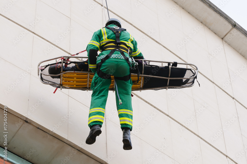 Paramedic is winched down a building on a rope with a patient during ...