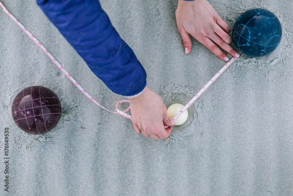 Measuring distance to determine winner of bocce game on beach Stock ...