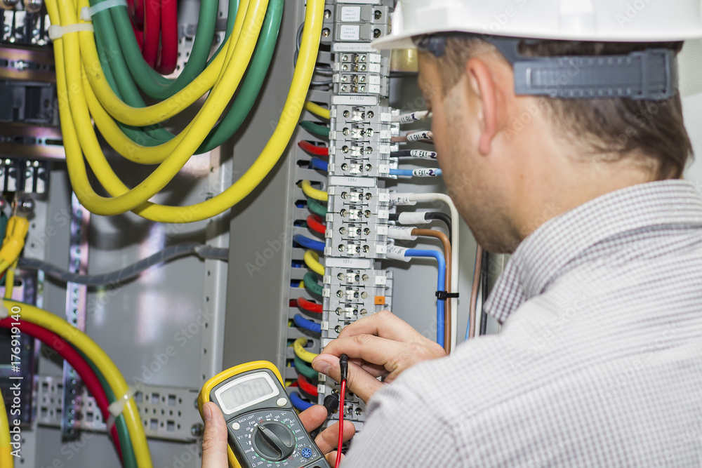 Engineer tests supply circuit in powerful panel of distribution cables ...