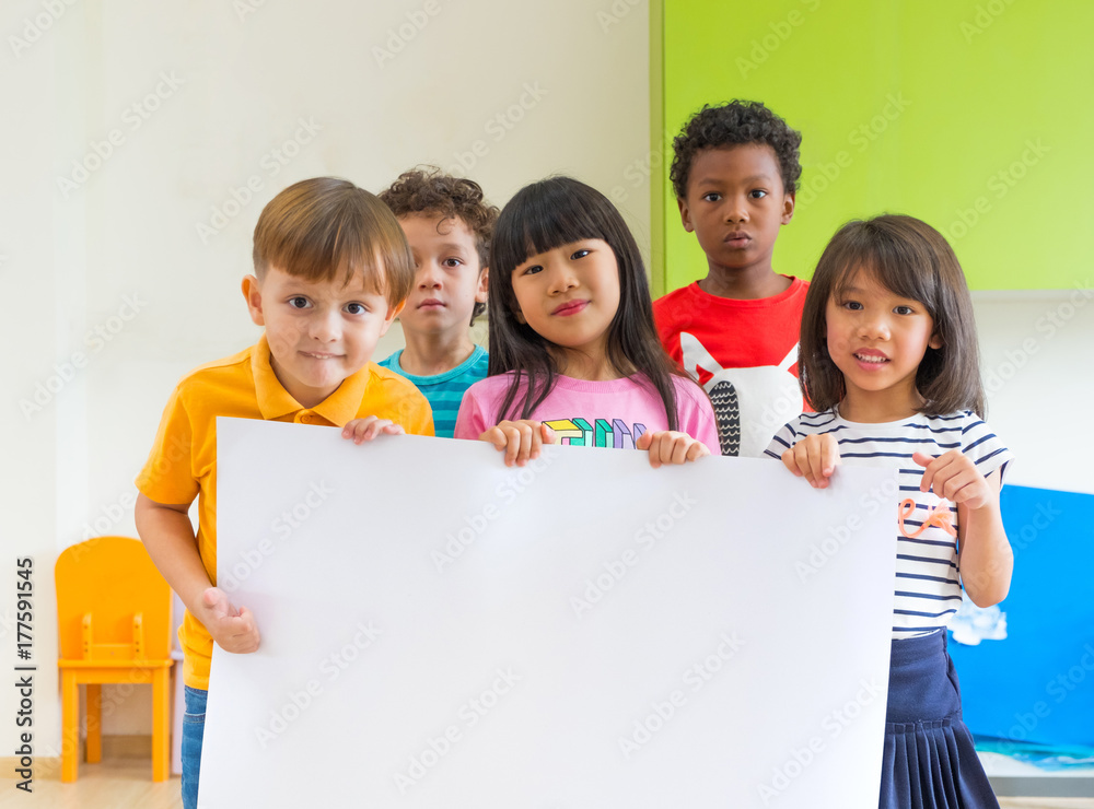 Diversity children holding blank poster in classroom at kindergarten ...