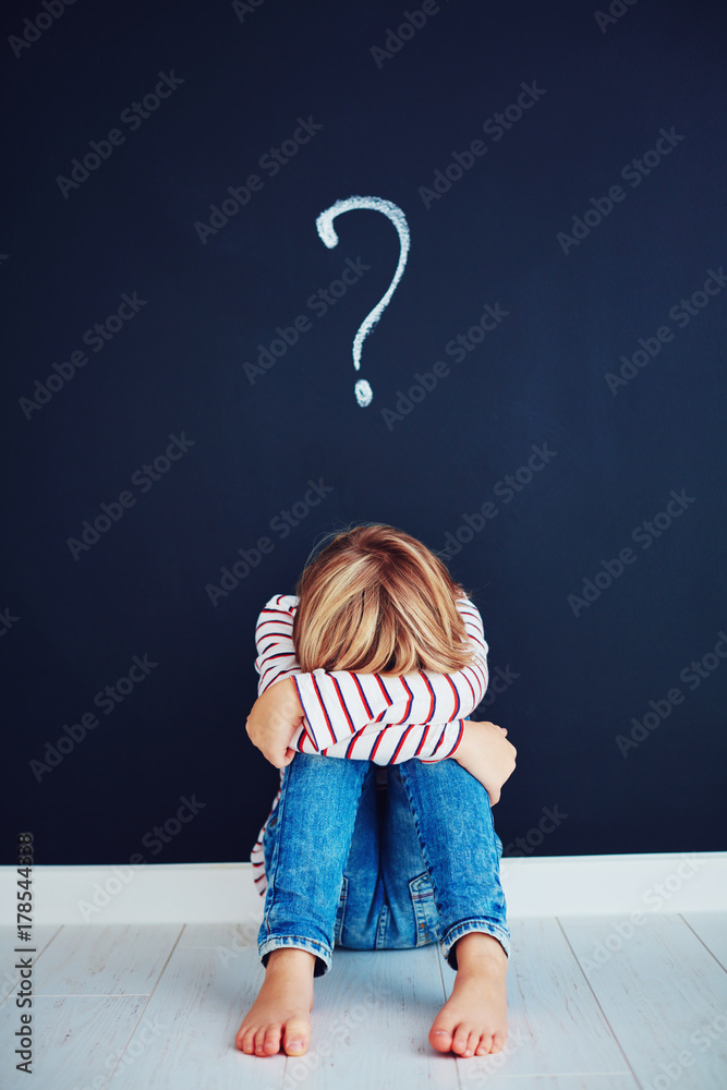 sad, frustrated school boy sitting on the floor with question mark ...