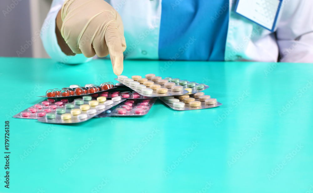 Female doctor hand hold pack of different tablet blisters at workplace ...