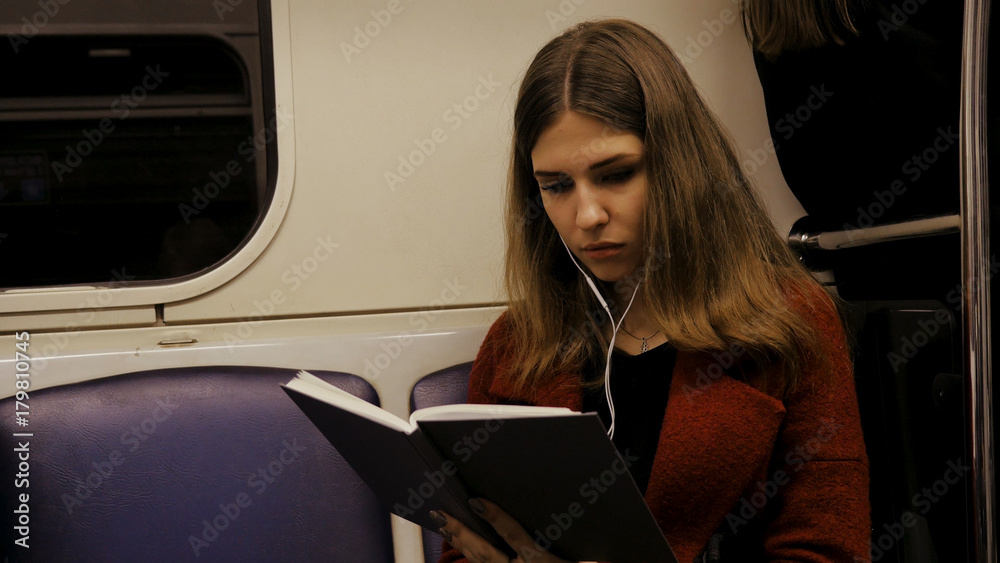 Young beautiful woman sitting on subway reading a book - commuter ...