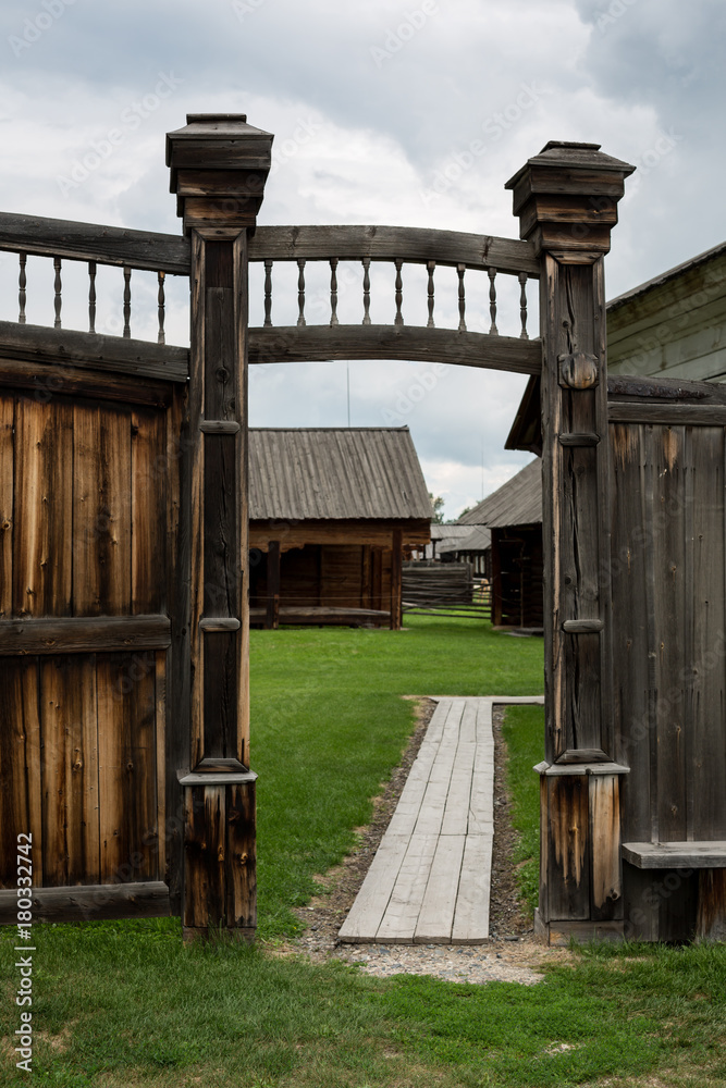 Old wooden gate with ornaments and a small roof with wickets on either ...