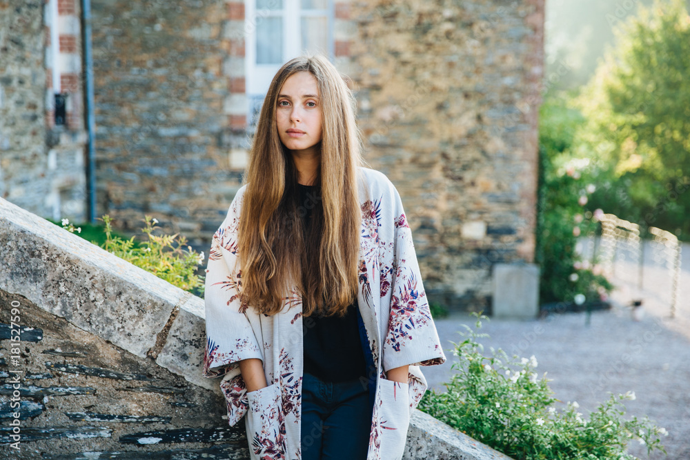 Beautiful female with long straight hair wears fashionable cape, stands ...