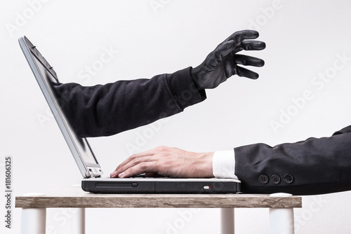 The abstract image of the hacker's hand reach through a laptop screen ...
