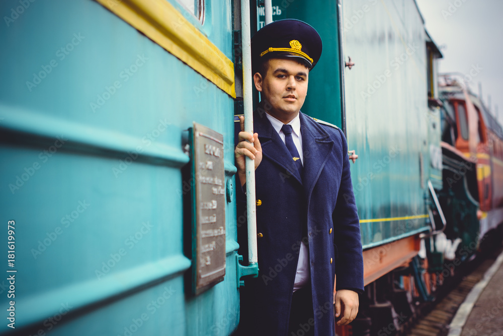 European or American train conductor is on his duty on a platform and ...